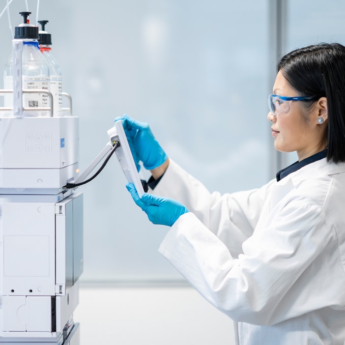 An HPLC scientist wearing a white lab coat and blue gloves is working ...