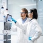 Two scientists wearing white lab coats operate a high-performance ...