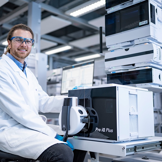 A male scientist in a white lab coat is sitting in front of a stack of ...