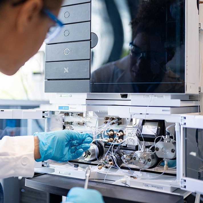 A scientist, wearing safety glasses, changes the tubing on the High ...